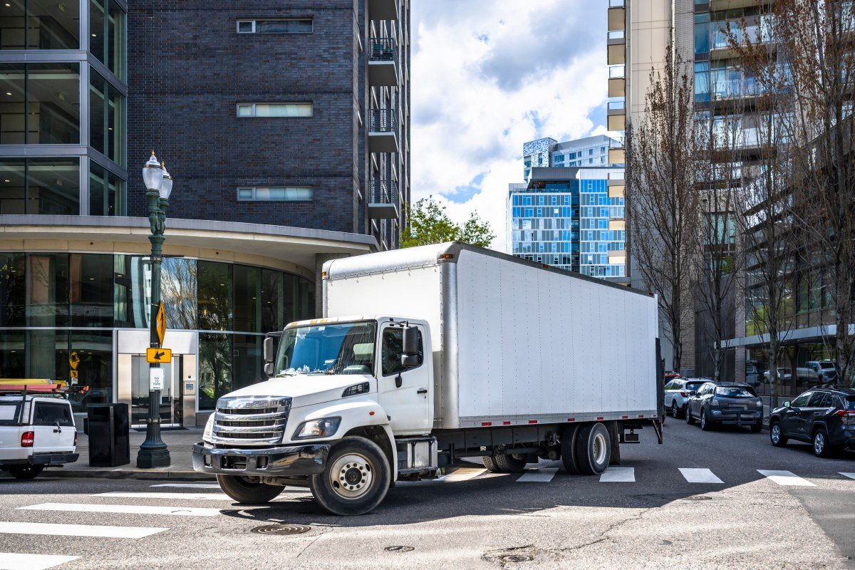 Big rig day cab white semi truck with long box trailer making lo ...